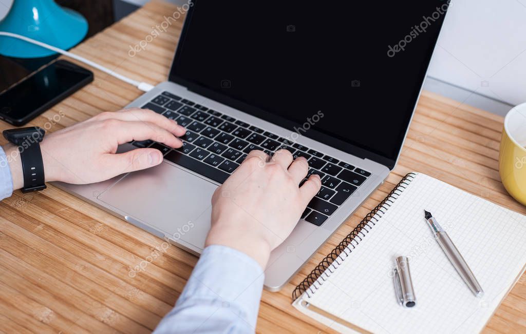Un hombre está trabajando mediante el uso de una computadora portátil en la mesa de madera ...