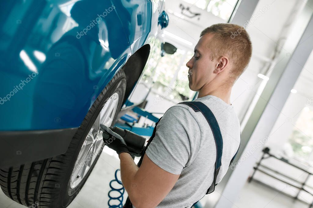 Mec nico masculino profesional que atornilla o desenrosca la rueda del coche del autom vil ...