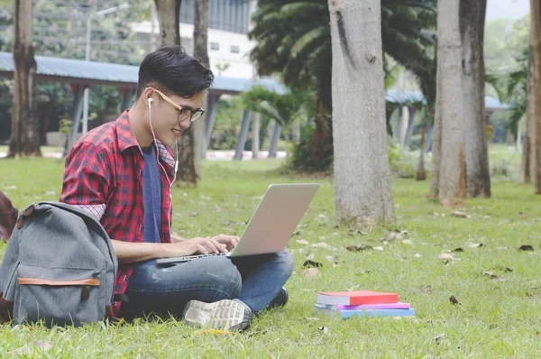 Asian attractive male student thinking about coursework strategy sitting in university garden ...