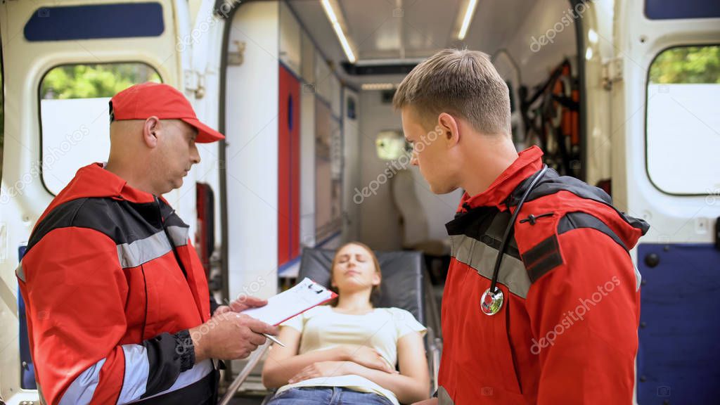 Paramédicos masculinos examinando al paciente en camilla, haciendo ...