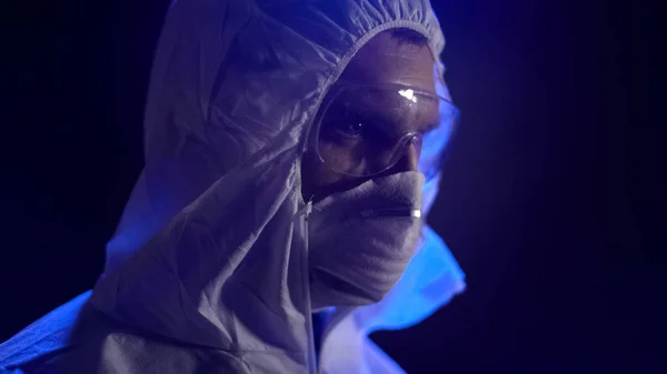 Chemist in lab costume wearing mask, secret manufacture of biological ...