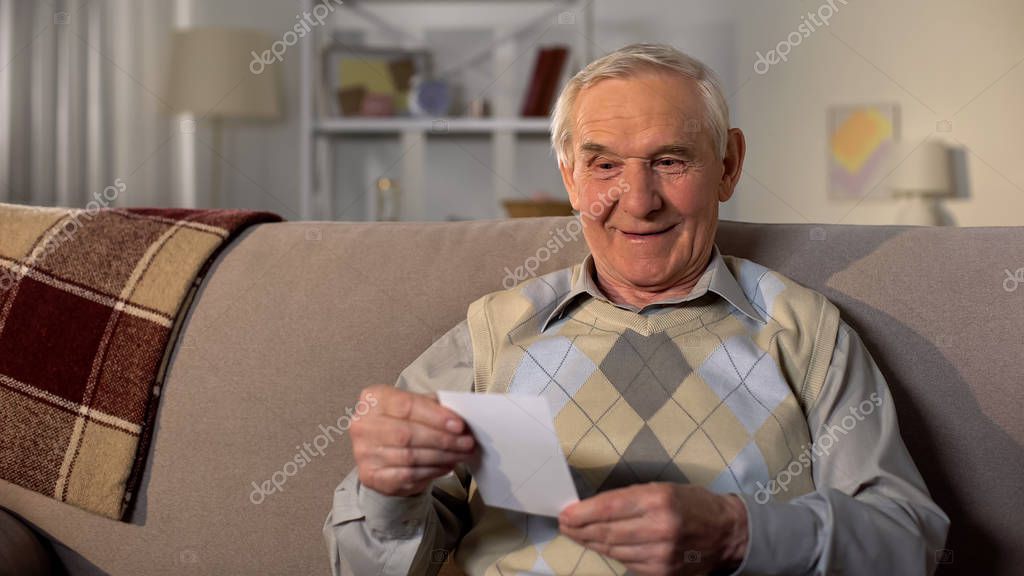 Feliz pensionista masculino mirando la foto sentado en casa sof , buenos recuerdos, sensaci n 2024