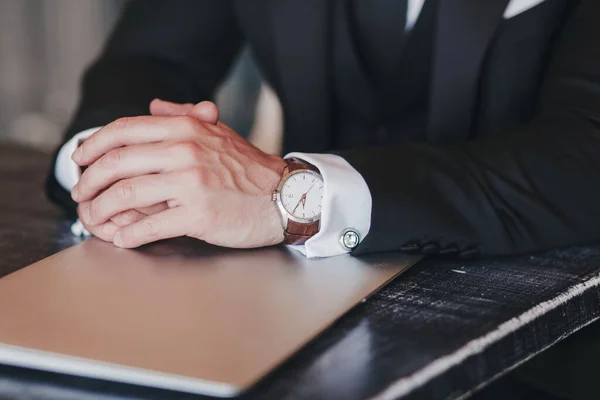 close-up of the hands of a successful man with a watch and laptop ...