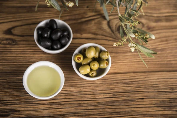 Olive oil, olive tree and green and black olives on a wooden tab ...