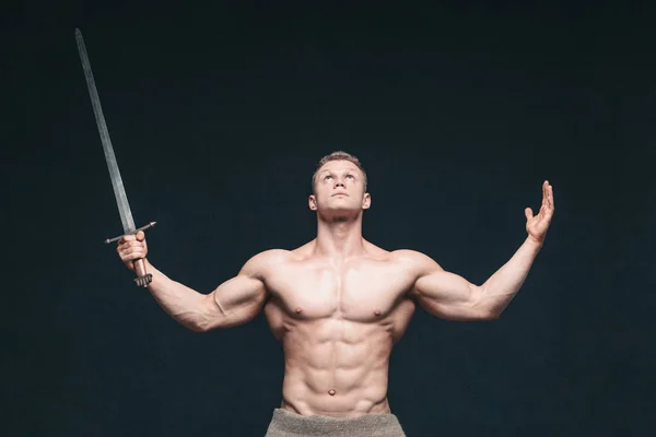 Bodybuilder man posing with a sword and shield isolated on white ...