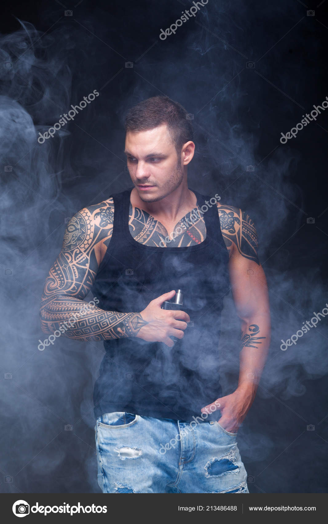 Vaper. The man with a muscular torso with tattoos smoke an electronic ...