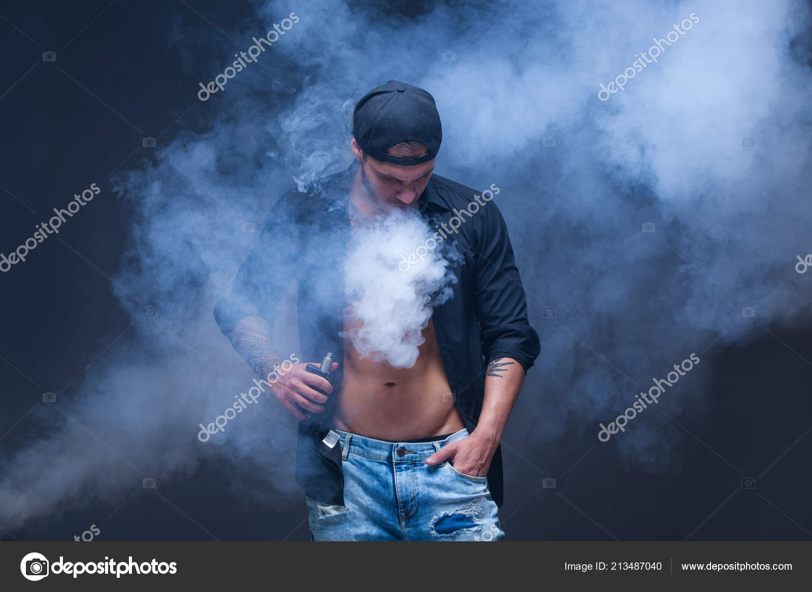 Vaper. The man dressed blue jeans, black shirt and black baseball cap ...