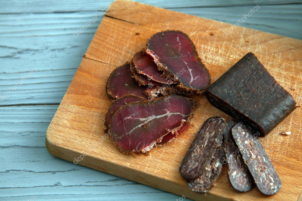 Rodajas de pastirma de ternera curada sobre tabla de madera. 2023
