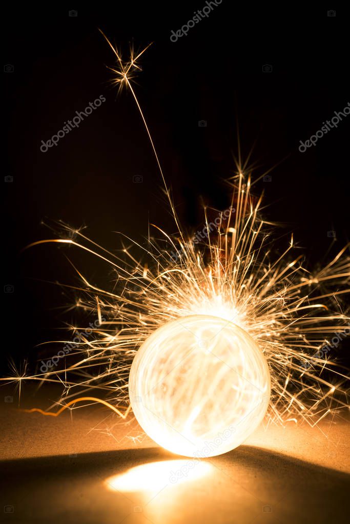 Brillo ardiente detrás de una bola de vidrio sobre un fondo negro. 2023