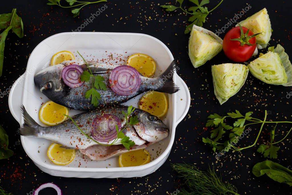 Listo para cocinar dos doradas enteras en cubiertos blancos con cebolla ...
