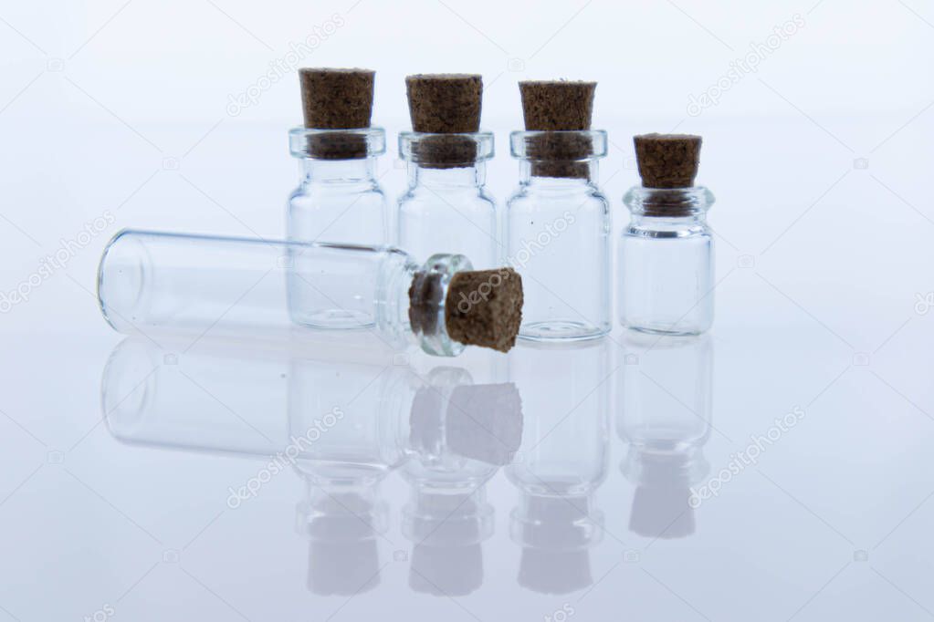 Frascos vacíos de vidrio transparente sellados con tapones de madera. Los objetos se reflejan en ...