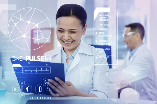 Happy lab worker smiling while looking at her notes - Stock Image ...