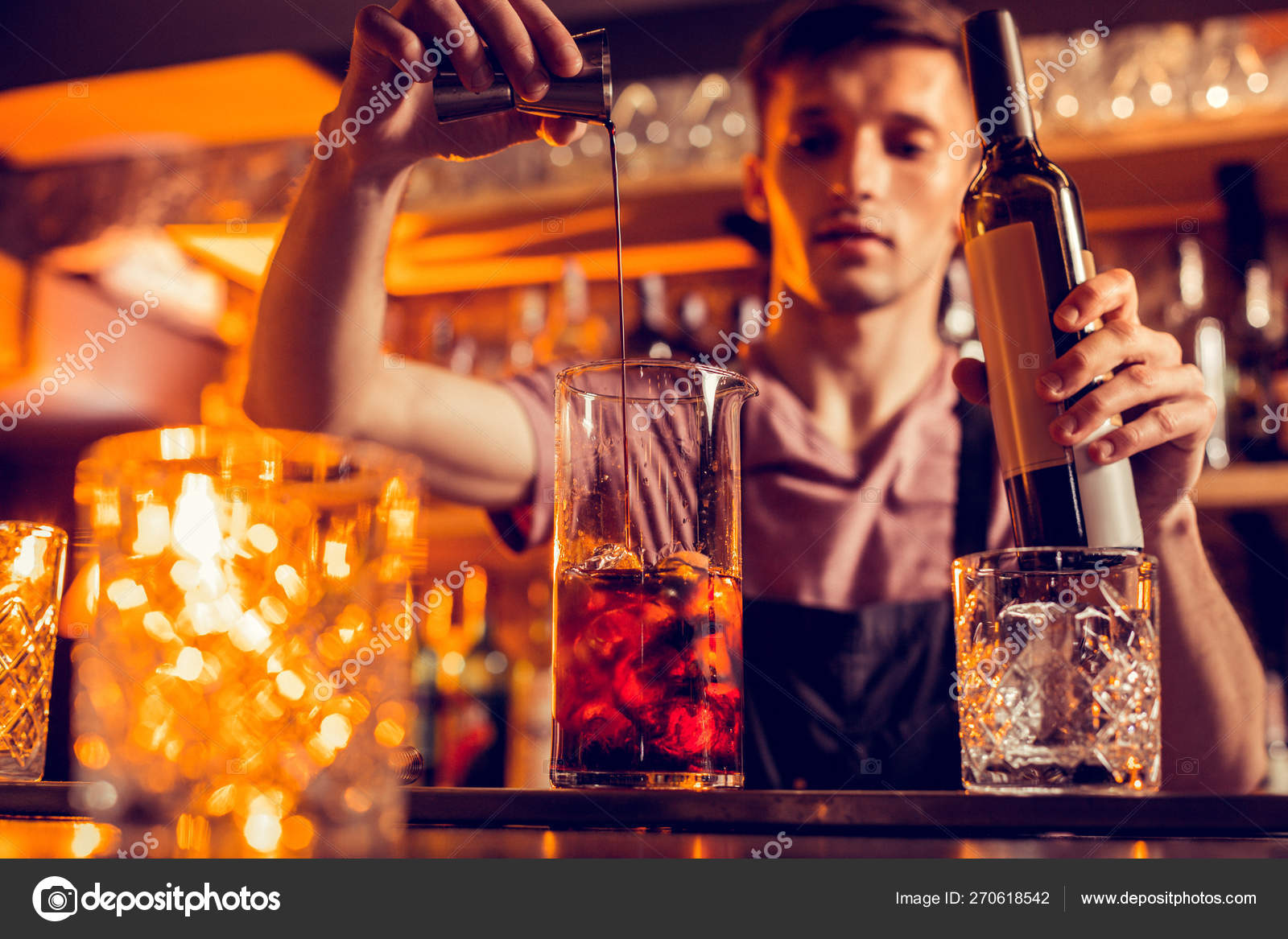 Handsome young barman pouring alcohol into cocktail — Stock Photo ...