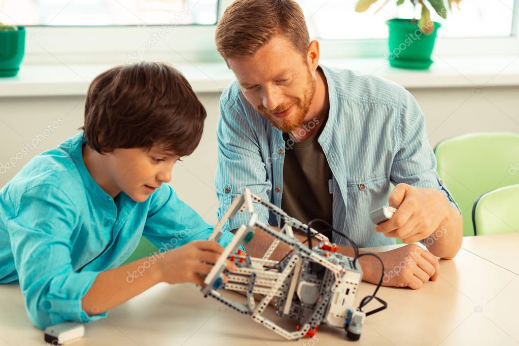 Profesora explicando al alumno el modo de operación de los robots. 2023