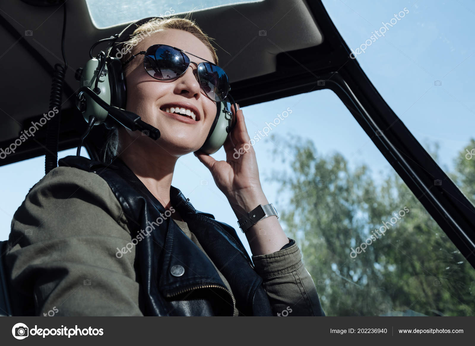 Cheerful helicopter pilot smiling while listening to air traffic ...