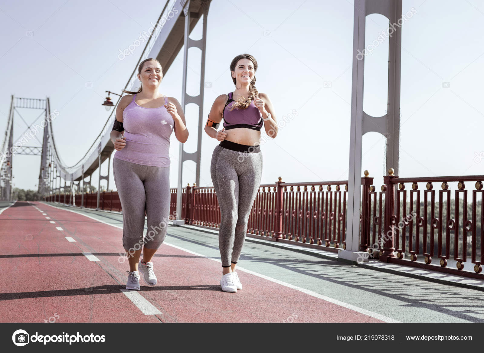 Nice positive women jogging together on the bridge Stock Photo by ...
