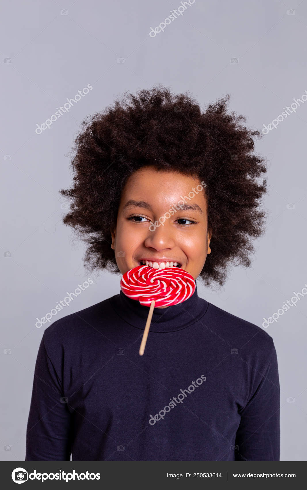 Funky dark-haired curly boy biting hard candy with strong teeth — Stock ...