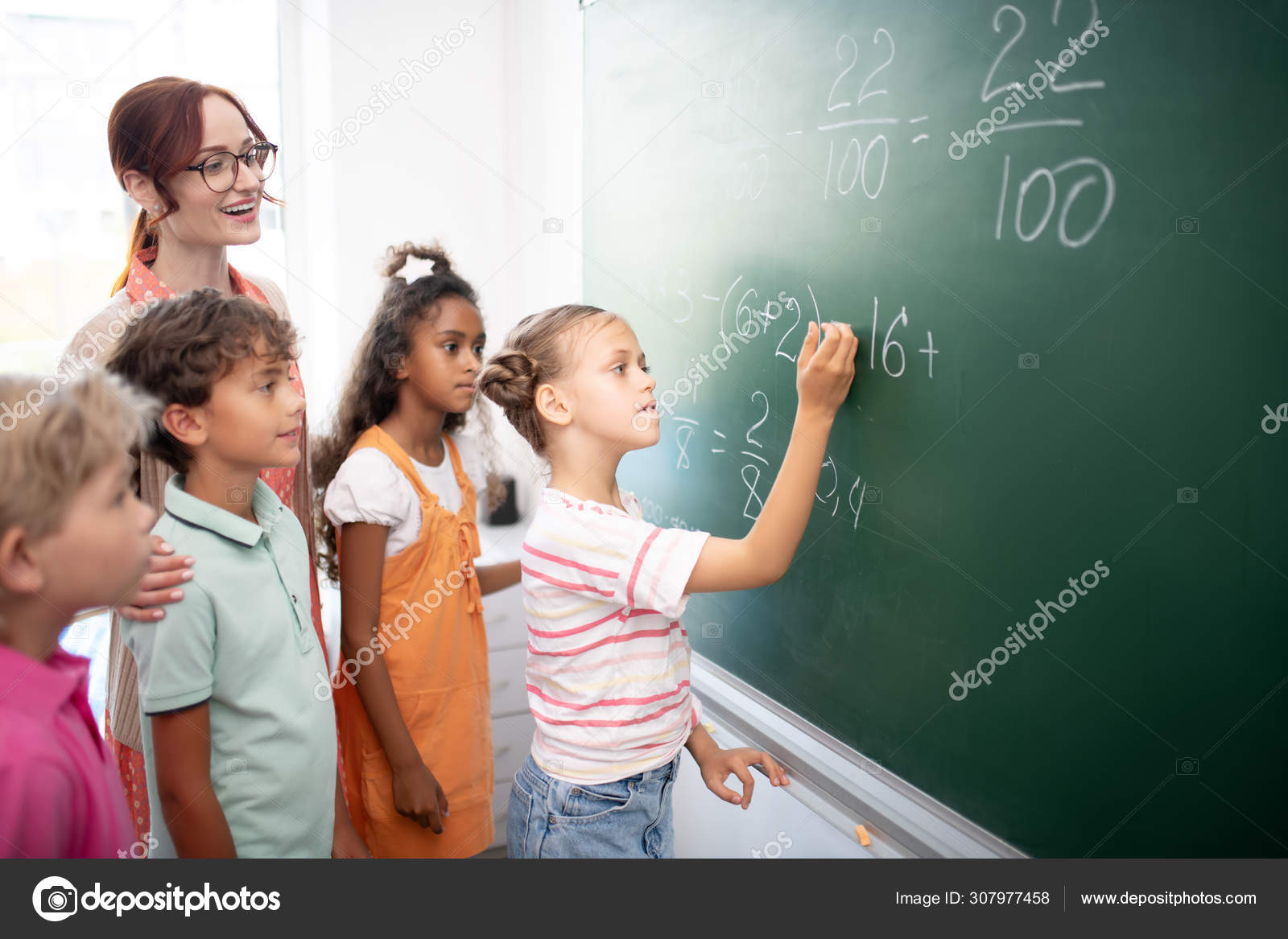 Smart girl writing down numbers on blackboard during math class Stock ...