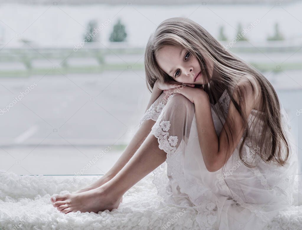 Una niña triste se sienta sola frente a la ventana. Soledad infantil ...