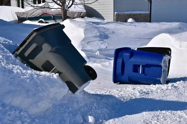 A garbage trash barrel and recycling bin are left turned over in the ...