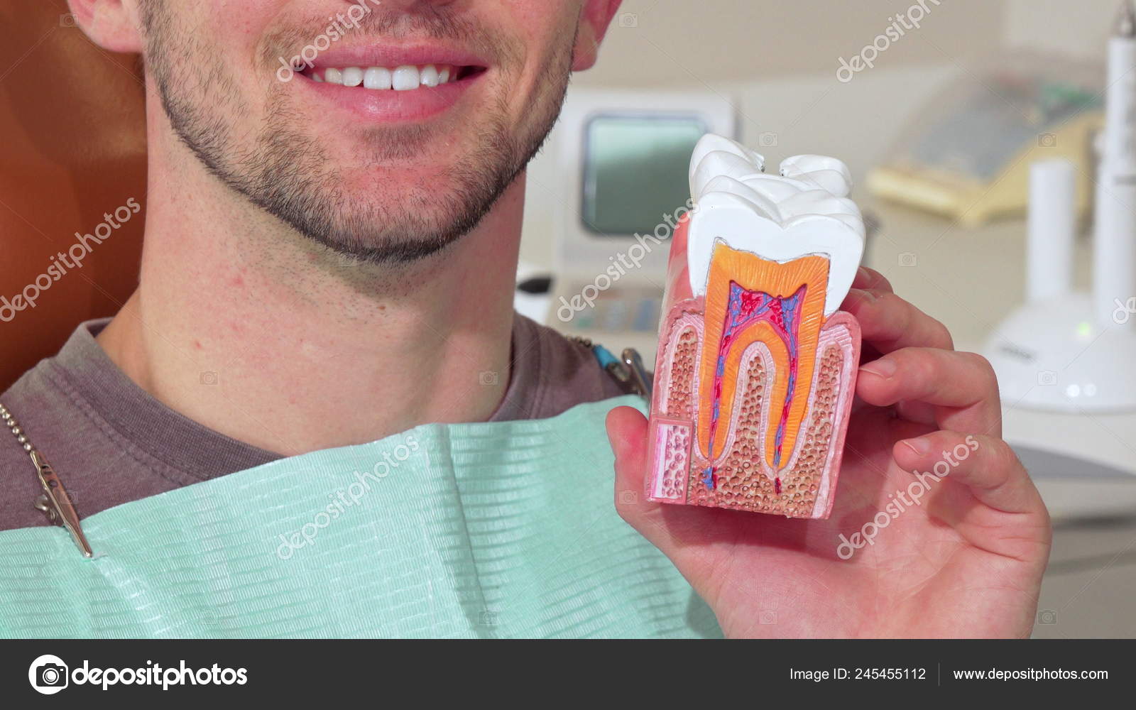 Man with white healthy teeth smiling, holding dental mold at the clinic ...