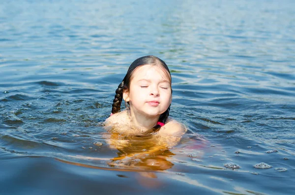 Happy child splashes on the ocean. The kid smiles and bathes in the sea ...