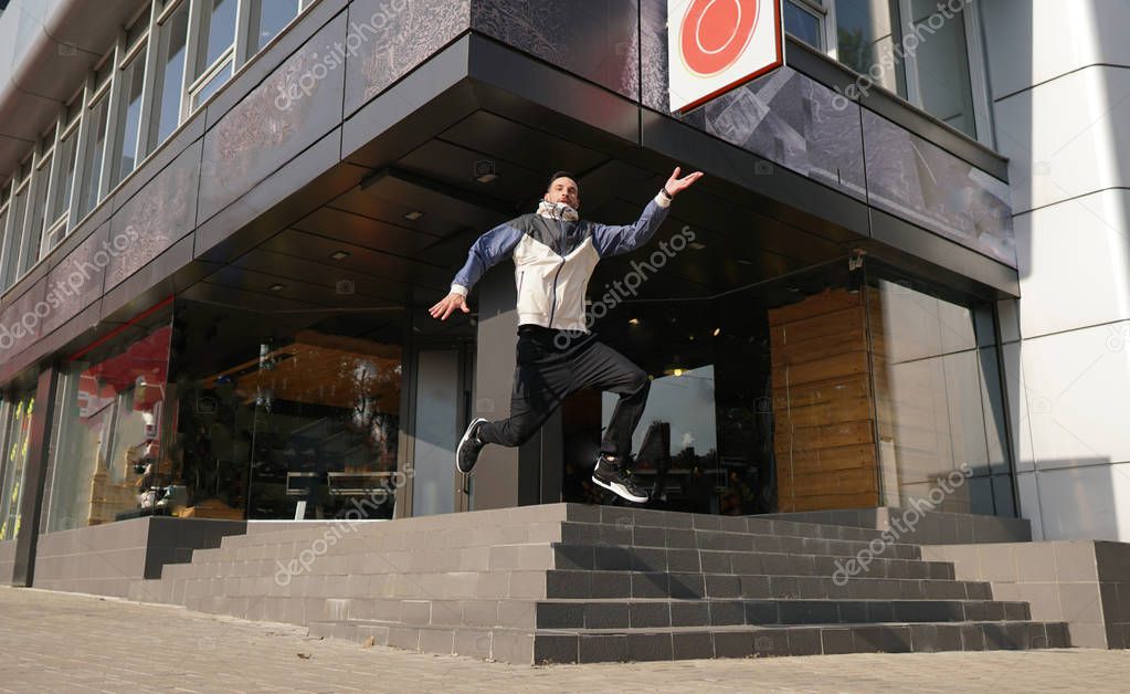 Joven chico atractivo saltando en frente de la tienda. Hombre saltando ...
