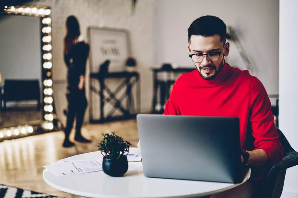 Positive male graphic designer updating software and working remotely at laptop computer using ...