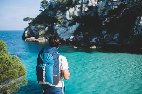 Back view of young man tourist with travel backpack enjoying beauty of ...