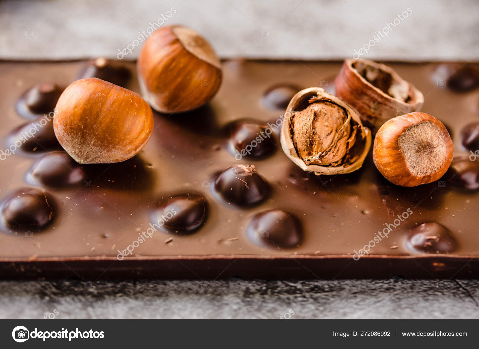 Dark chocolate with hazelnuts in the shel on gray backgroundl, c ...