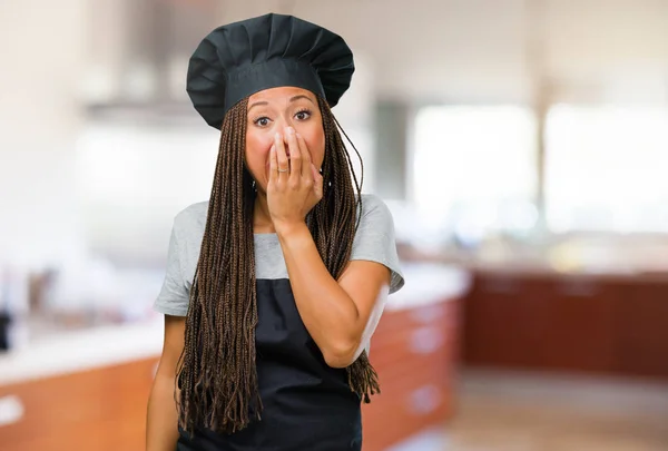 Portrait of a young black baker woman very scared and afraid, desperate ...