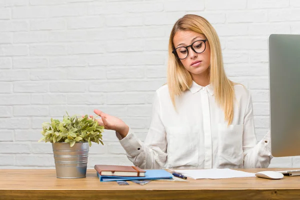 Portrait of young student sitting on her desk doing tasks doubting and ...