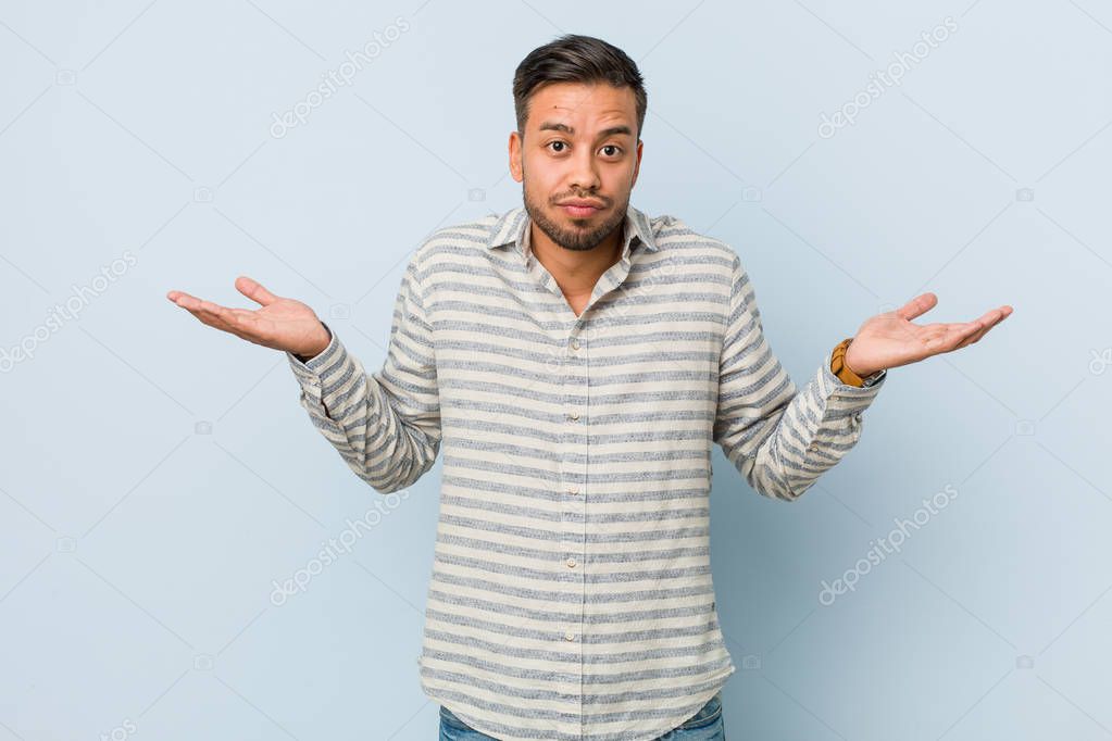 Joven hombre filipino guapo dudando y encogiéndose de hombros en gesto ...