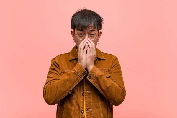 Young chinese man wearing a jacket very scared and afraid hidden ...
