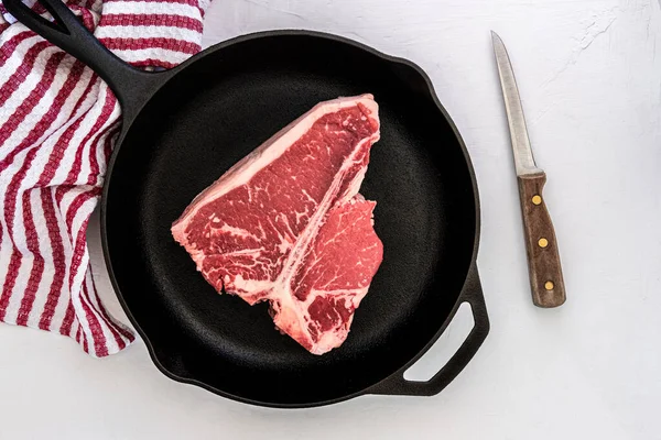 Photograph of a T-Bone choice cut steak in a cast iron skillet with a ...