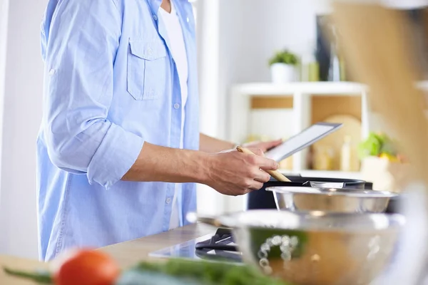 Man following recipe on digital tablet and cooking tasty and healthy ...