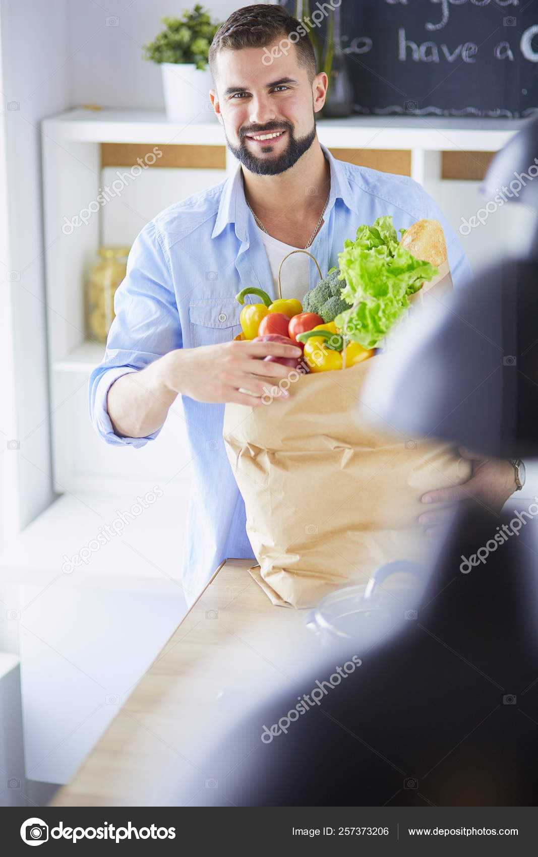 Man holding paper bag full of groceries on the kitchen background ...