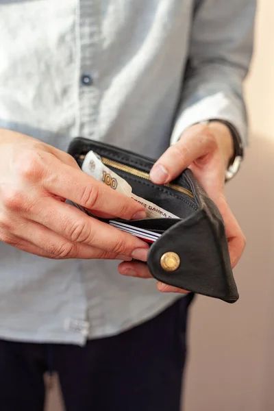 male hands hold a purse. A wallet with little money in it. The concept ...