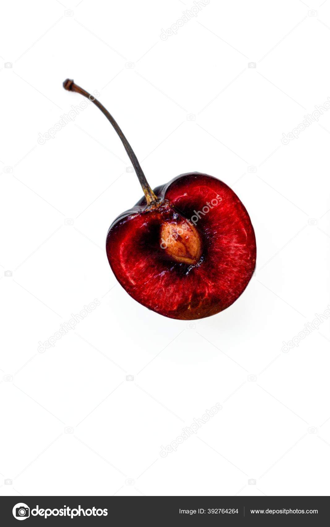 Bright ripe juicy cherry cut in half with a bone inside on a white ...