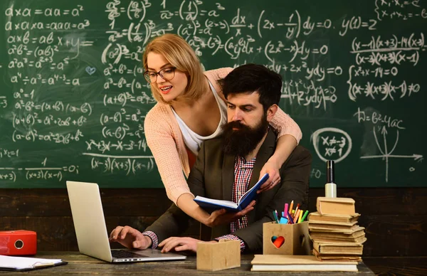 Pretty teacher helping pupil in classroom at the elementary school ...