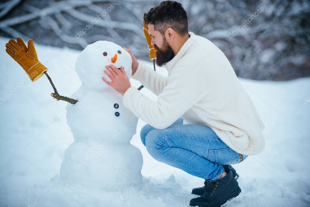 Muñeco de nieve y hombre barbudo divertido en la nieve. Hombre jugando ...