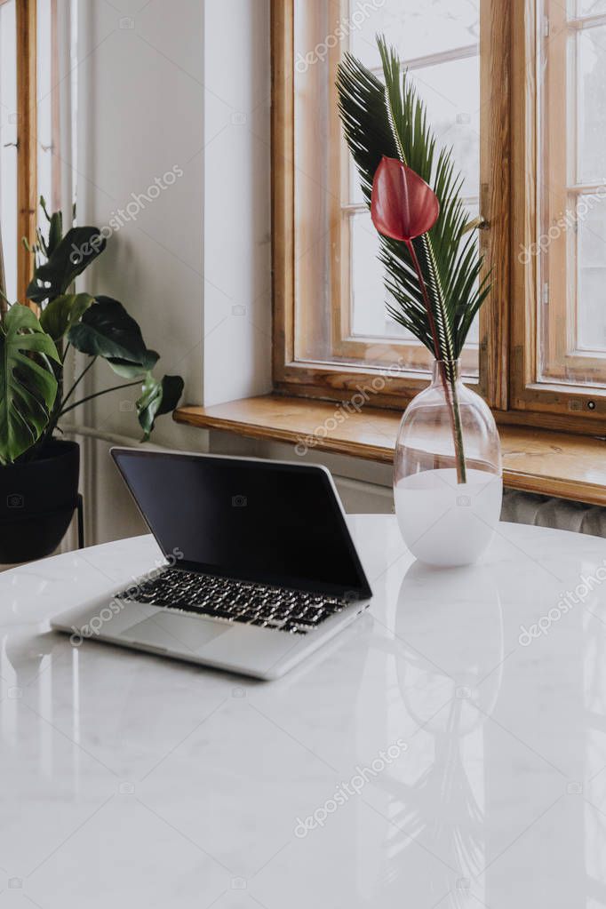 Portátil y un jarrón en una mesa de mármol 2025