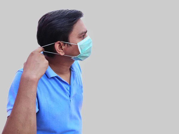 Man wearing Face mask pulling mark strings to place it over Ears ...