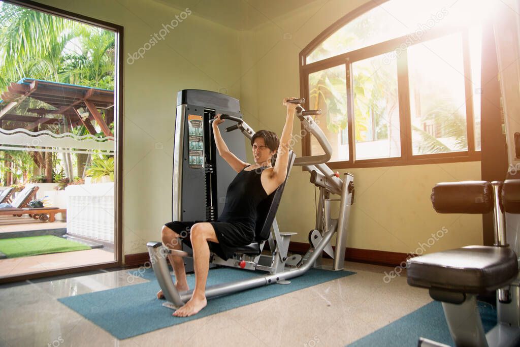 El macho asiático haciendo ejercicio para los músculos del pecho en la ...