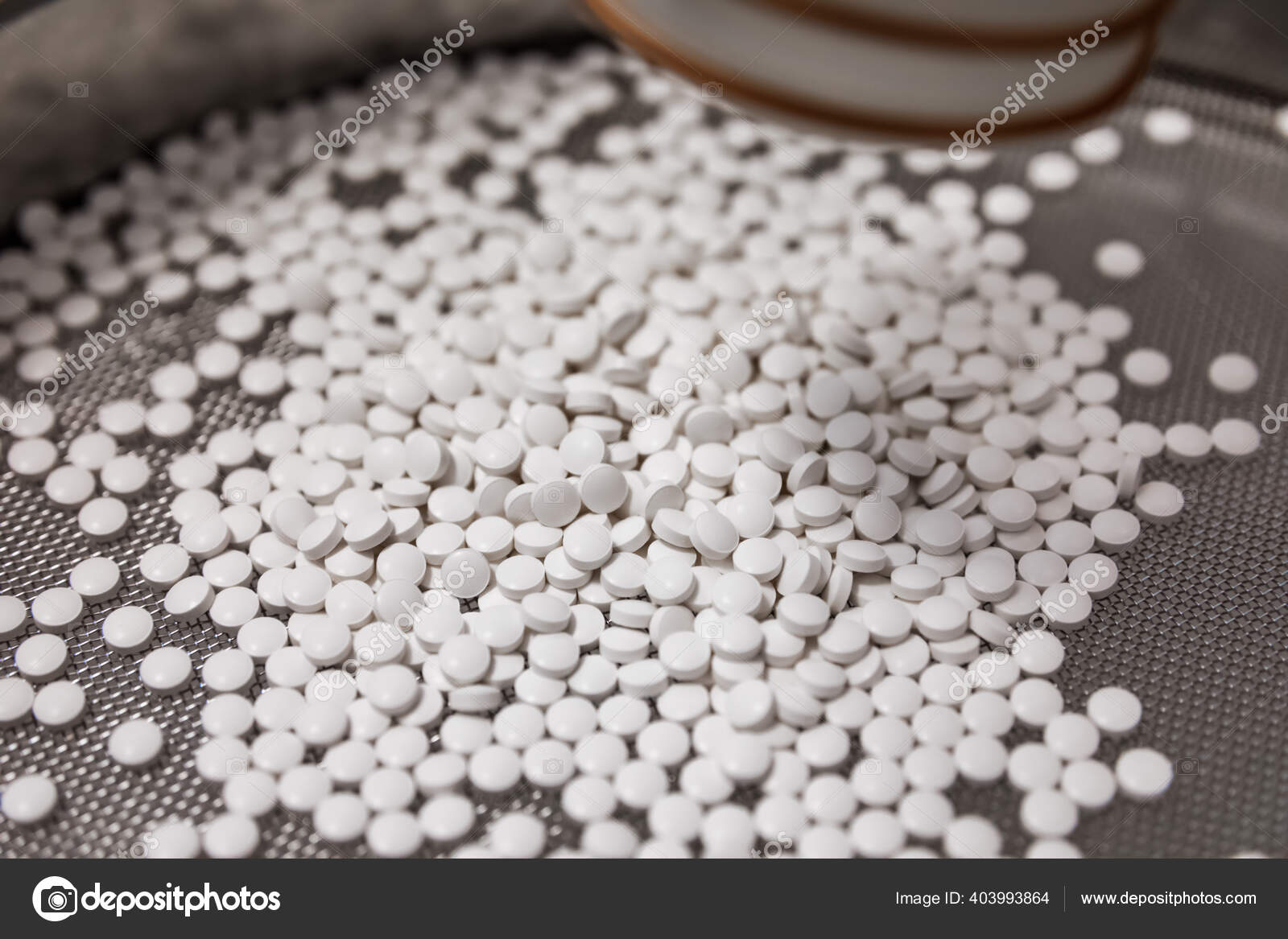 Lots of white tablets are poured onto a special sieve. Abstract medical ...