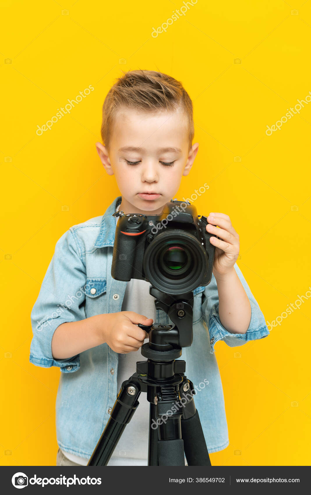 Cute puzzled kid adjusts the camera on tripod — Stock Photo © Youzhny ...