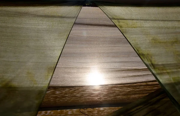 texture of brown tent, sun behind fabric texture, back lit, sunny day ...