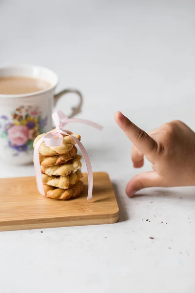 Tasty stack of homemade biscuits with pink ribbon on wooden board and a ...