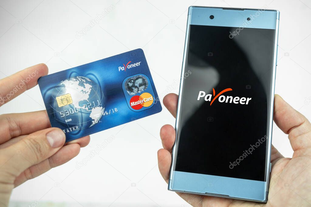 Tarjeta Payoneer en una mano y aplicación en un teléfono inteligente ...