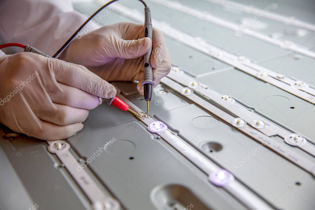 Reparación de televisor led con multímetro digital, control de tiras led. El ingeniero mide el ...